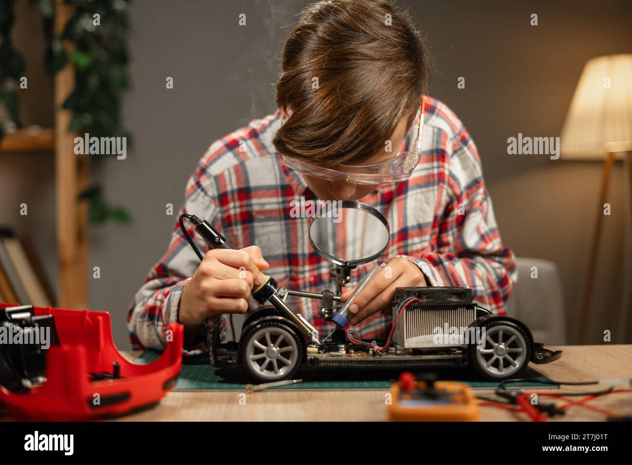 Young teenage schoolboy studying electronics, soldering wires in a ...