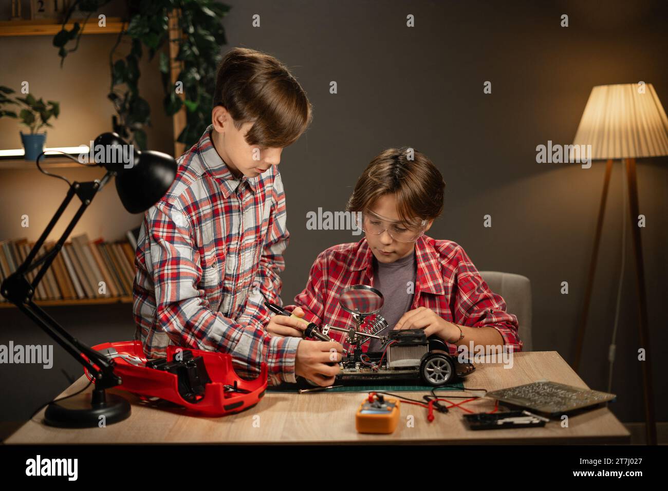 Smart young teenage boys studying electronics and soldering wires in ...