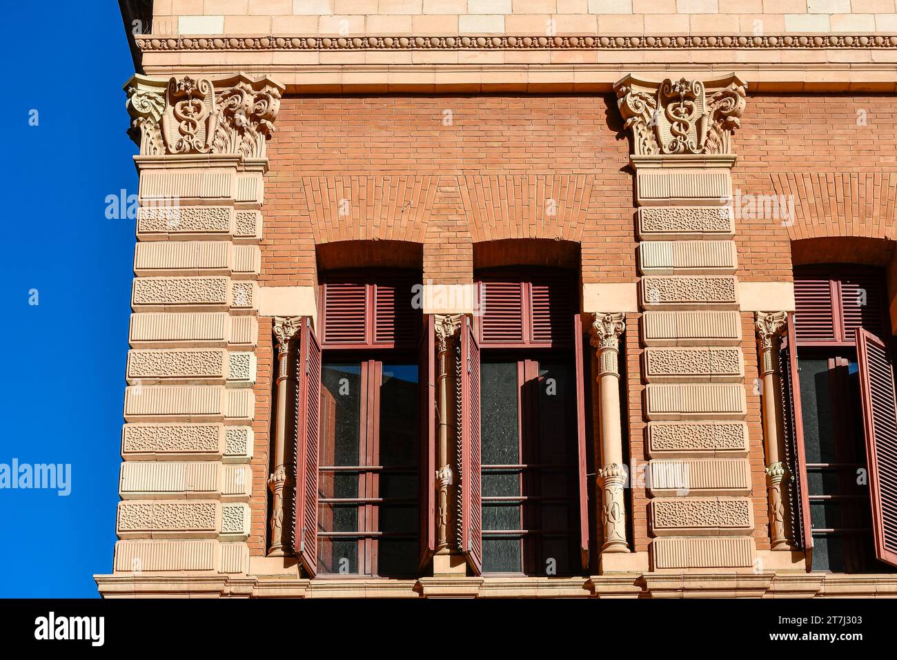 An ornate red brick building with three large arched windows Stock ...
