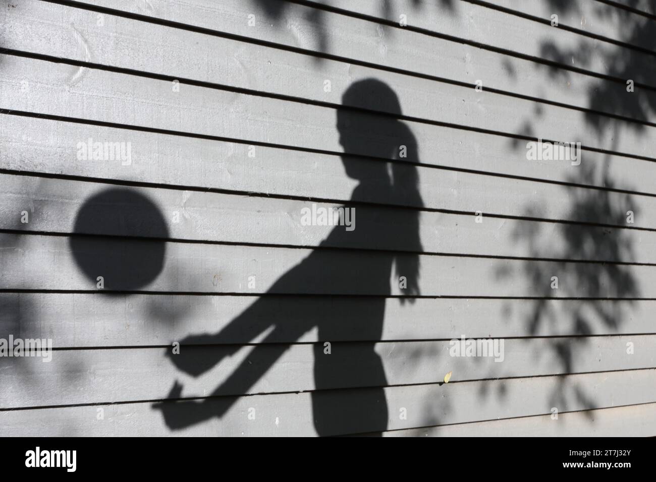 Teenage girl practises volleyball shots shadow with ball in mid air ...