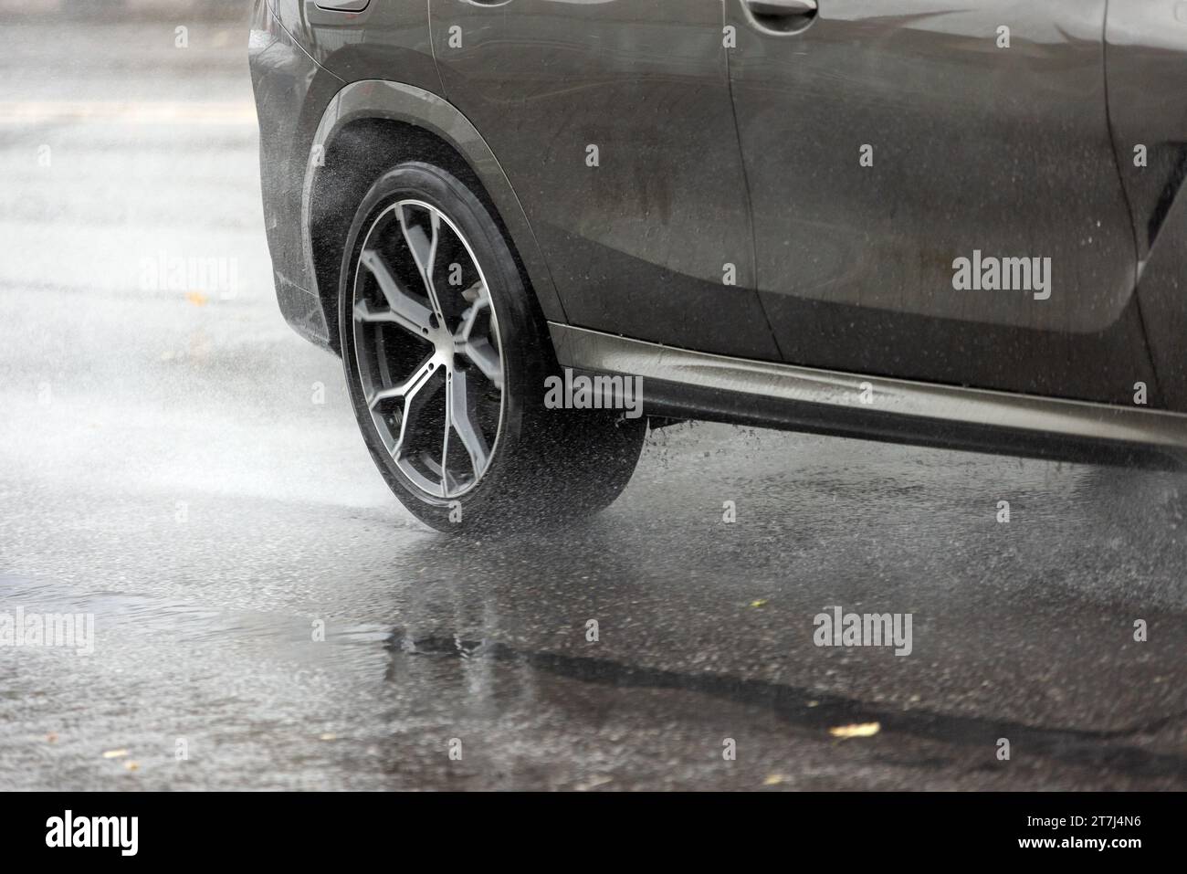 rain water splashing flows from wheels of grey car that moving fast on ...