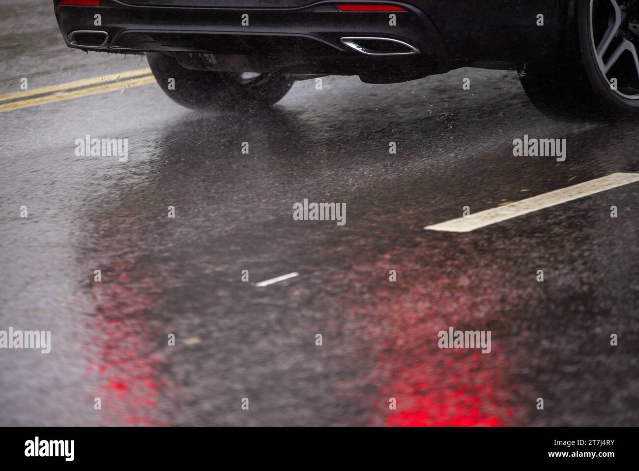 rain water splashing flows from wheels of black car that moving fast on ...
