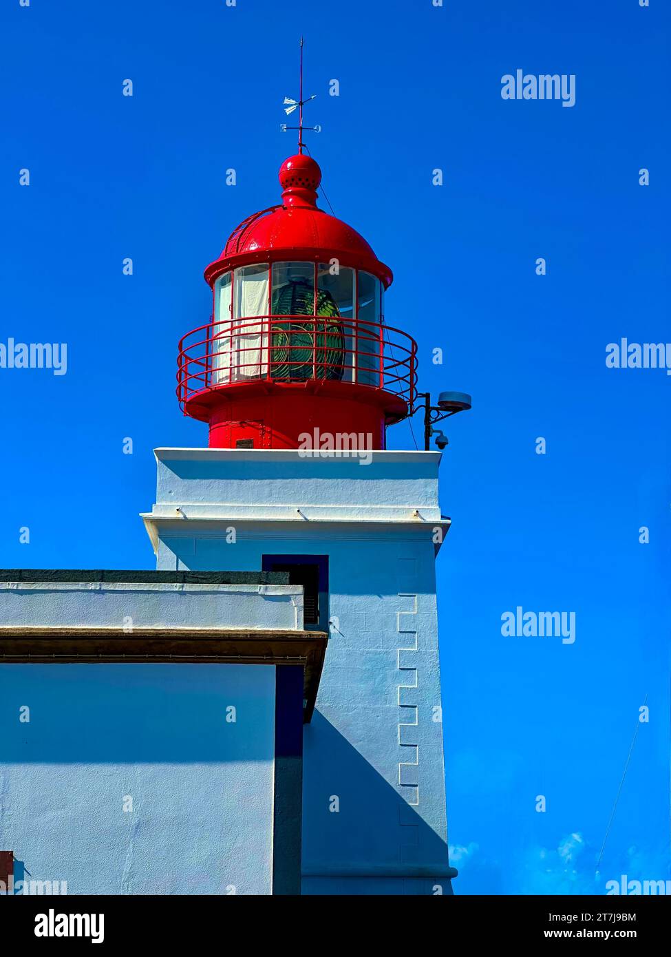 A lighthouse painted in red and white stands tall on Madeira's western ...
