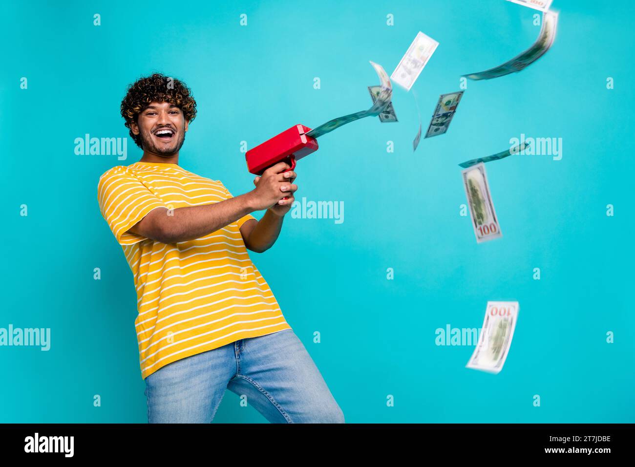 Portrait of positive excited wealthy guy hold money gun shooting dollar ...