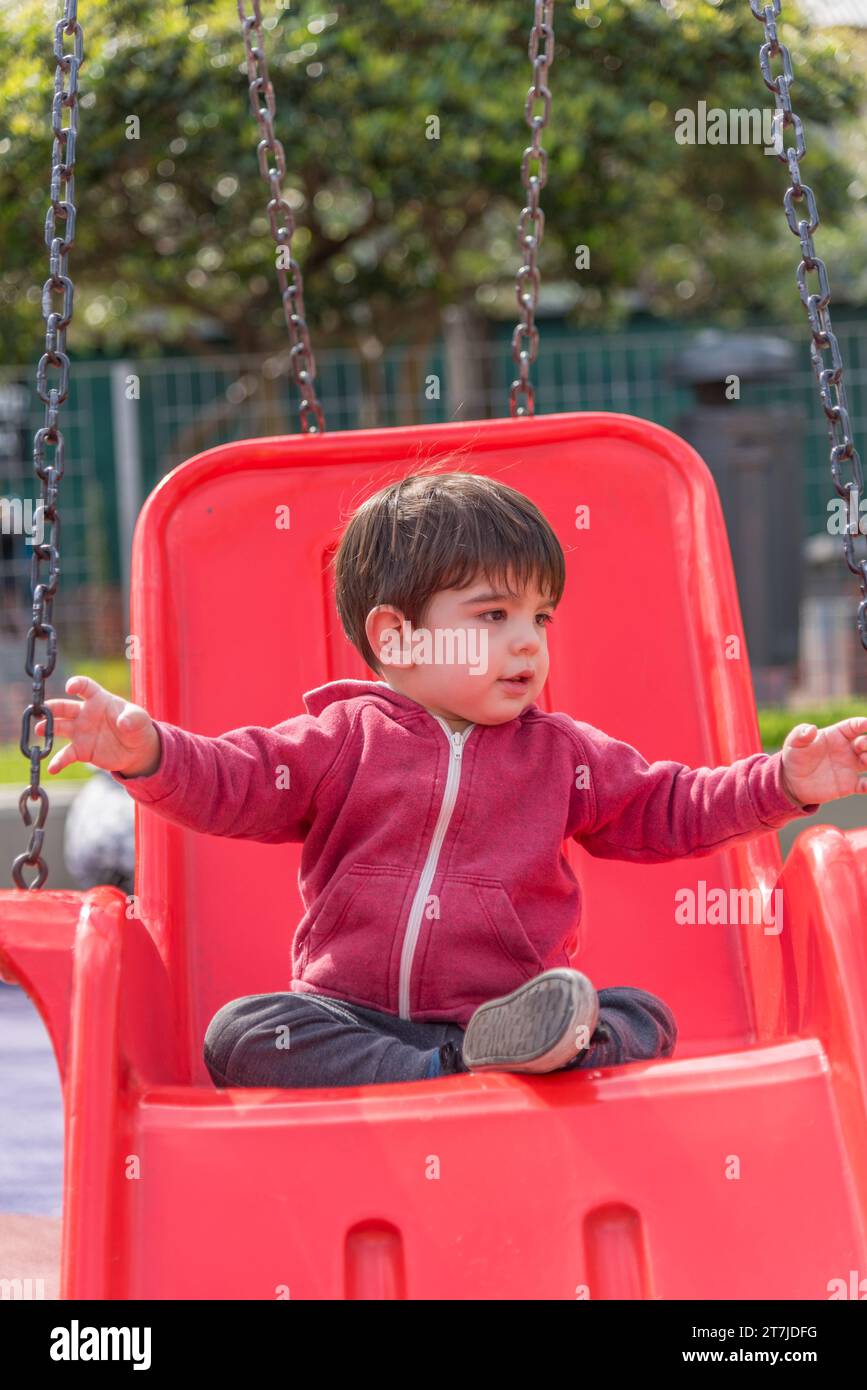 Little boy swinging on the swing at the playground in the park Stock ...