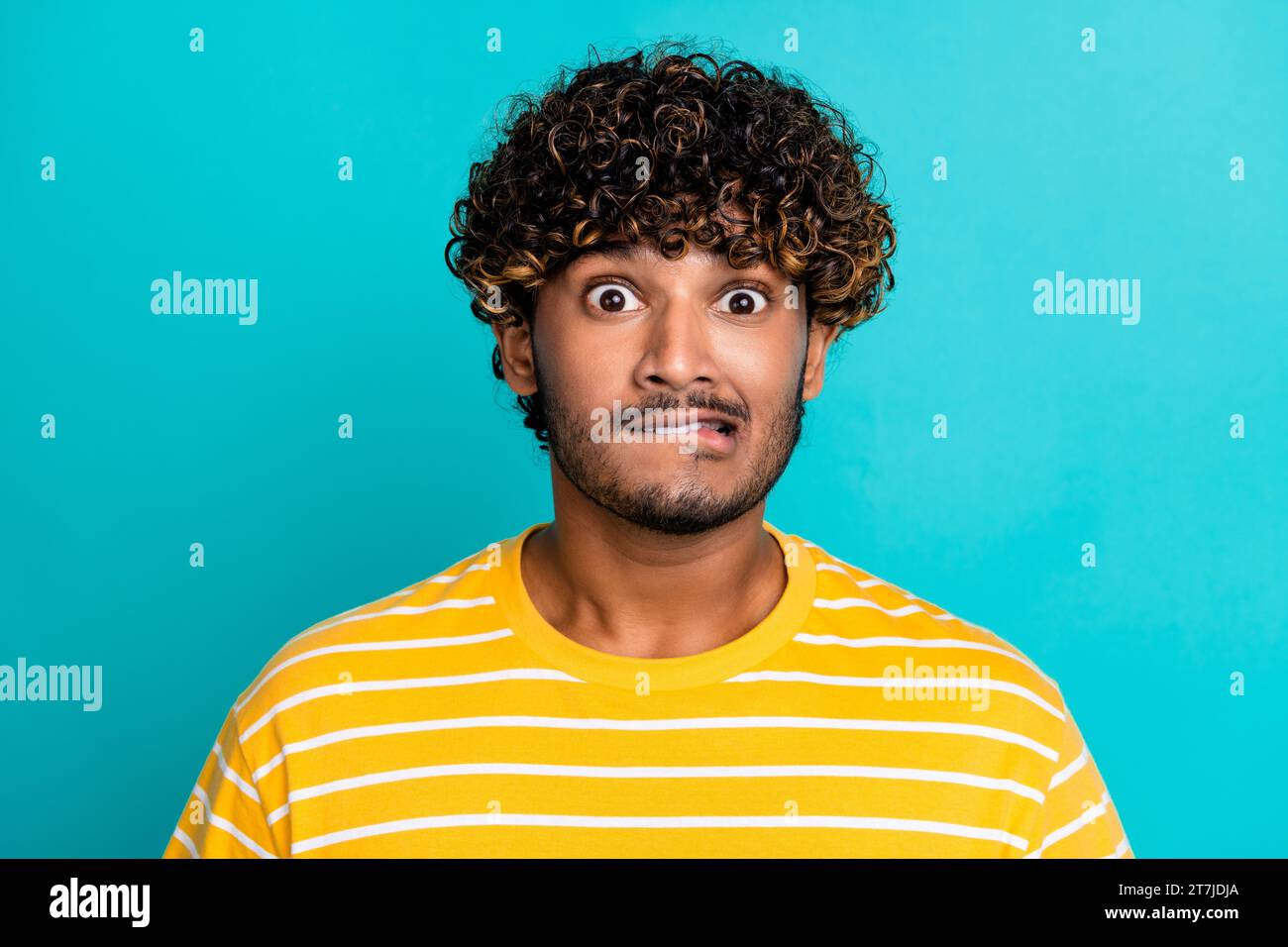 Photo of impressed nervous young man wavy hairdo biting lips staring ...