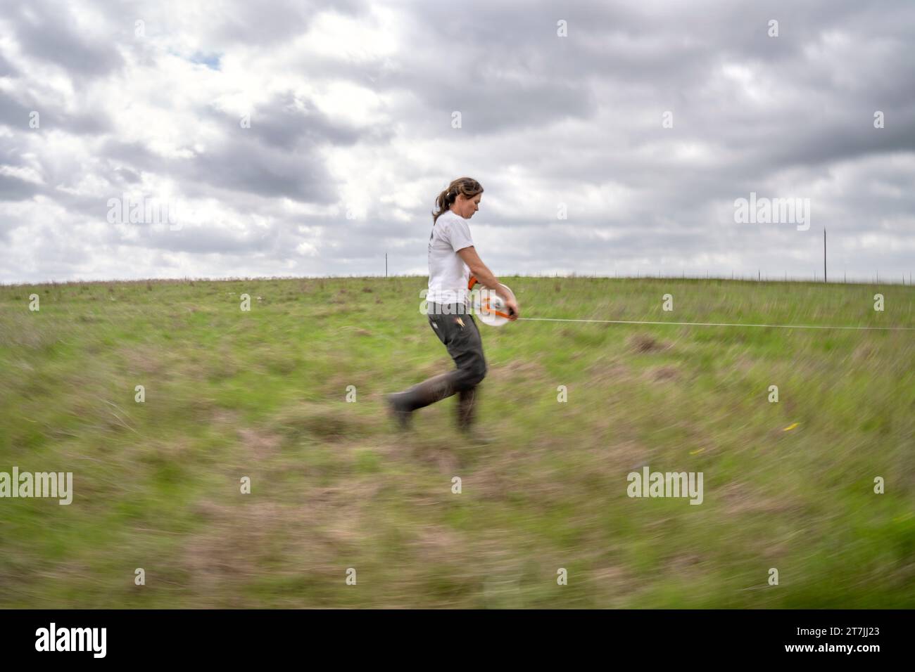 Meredith Ellis winds up a line of electric fence as she opens up a ...