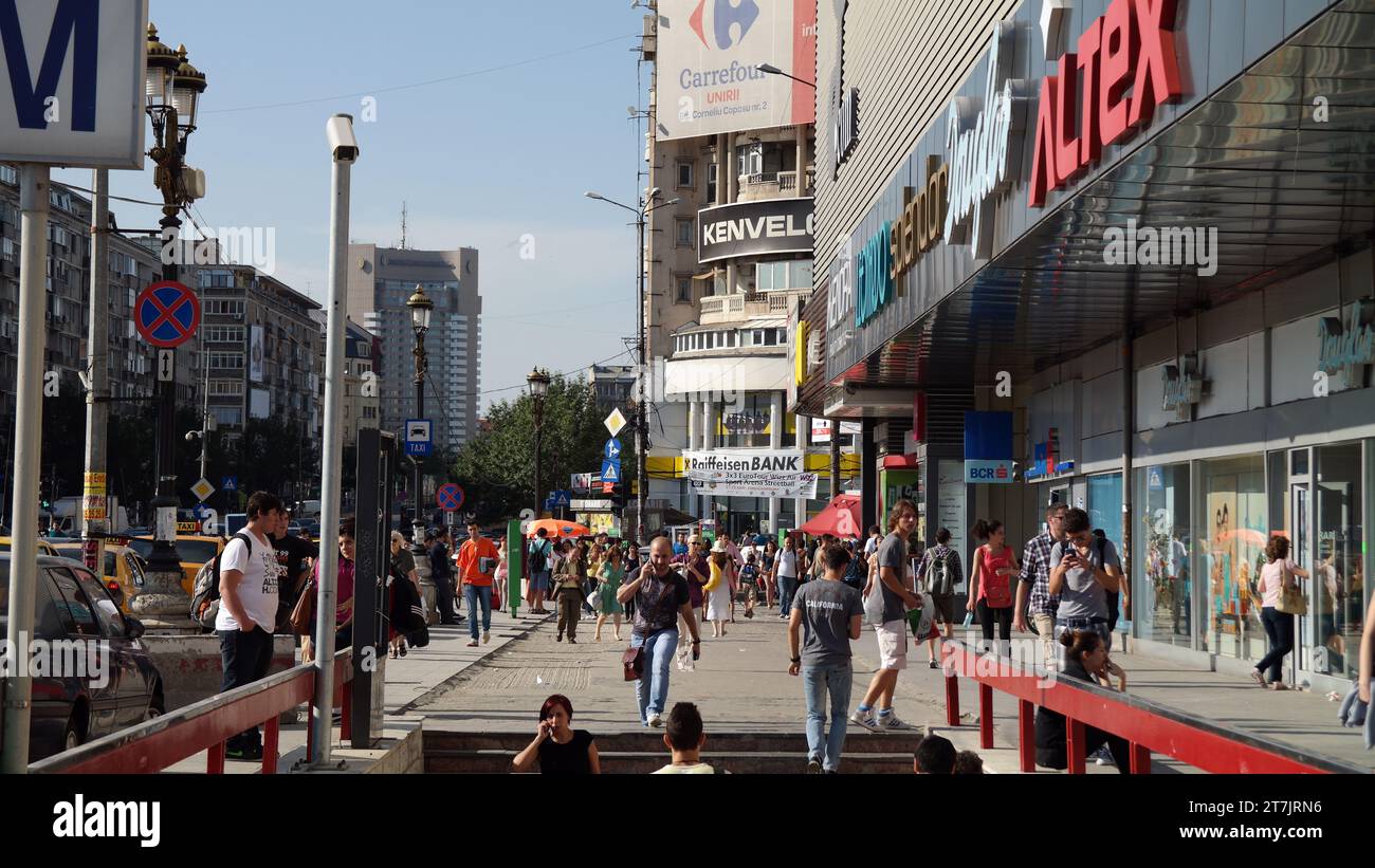 A diverse group of people are seen strolling down a busy urban street ...