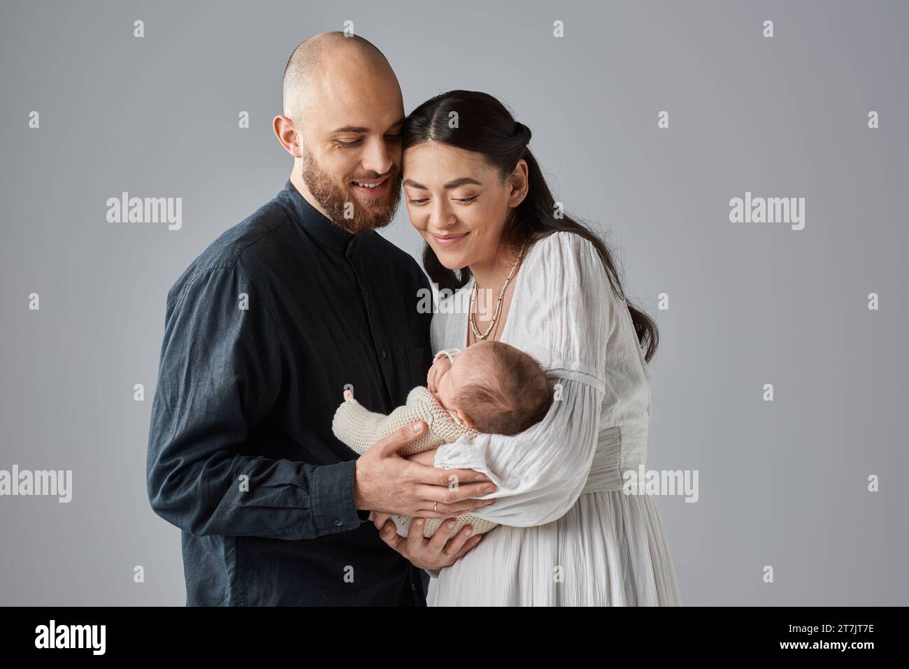 joyous modern parents in classy outfits smiling at their newborn baby ...