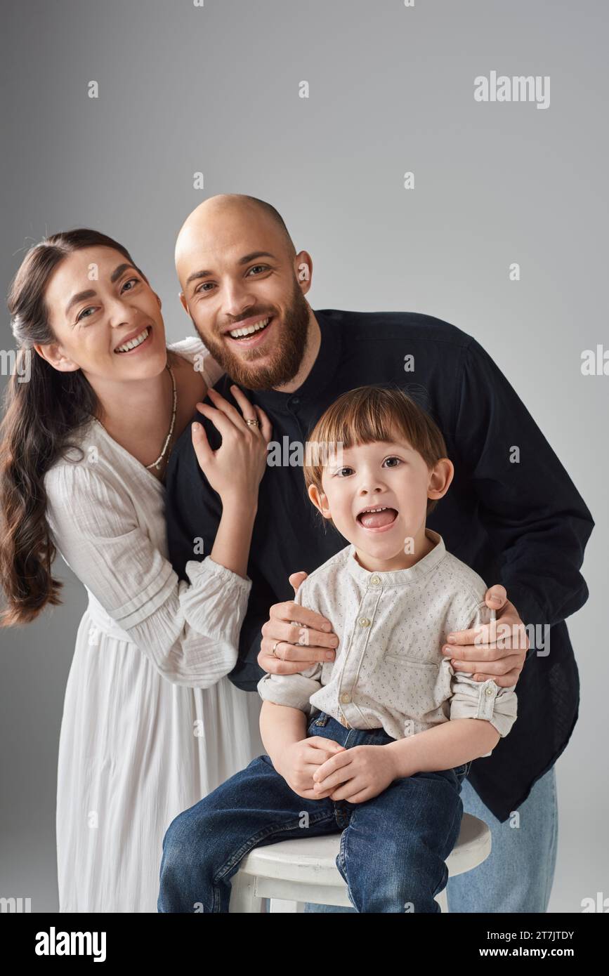 vertical shot of jolly modern parents hugging their little son that ...