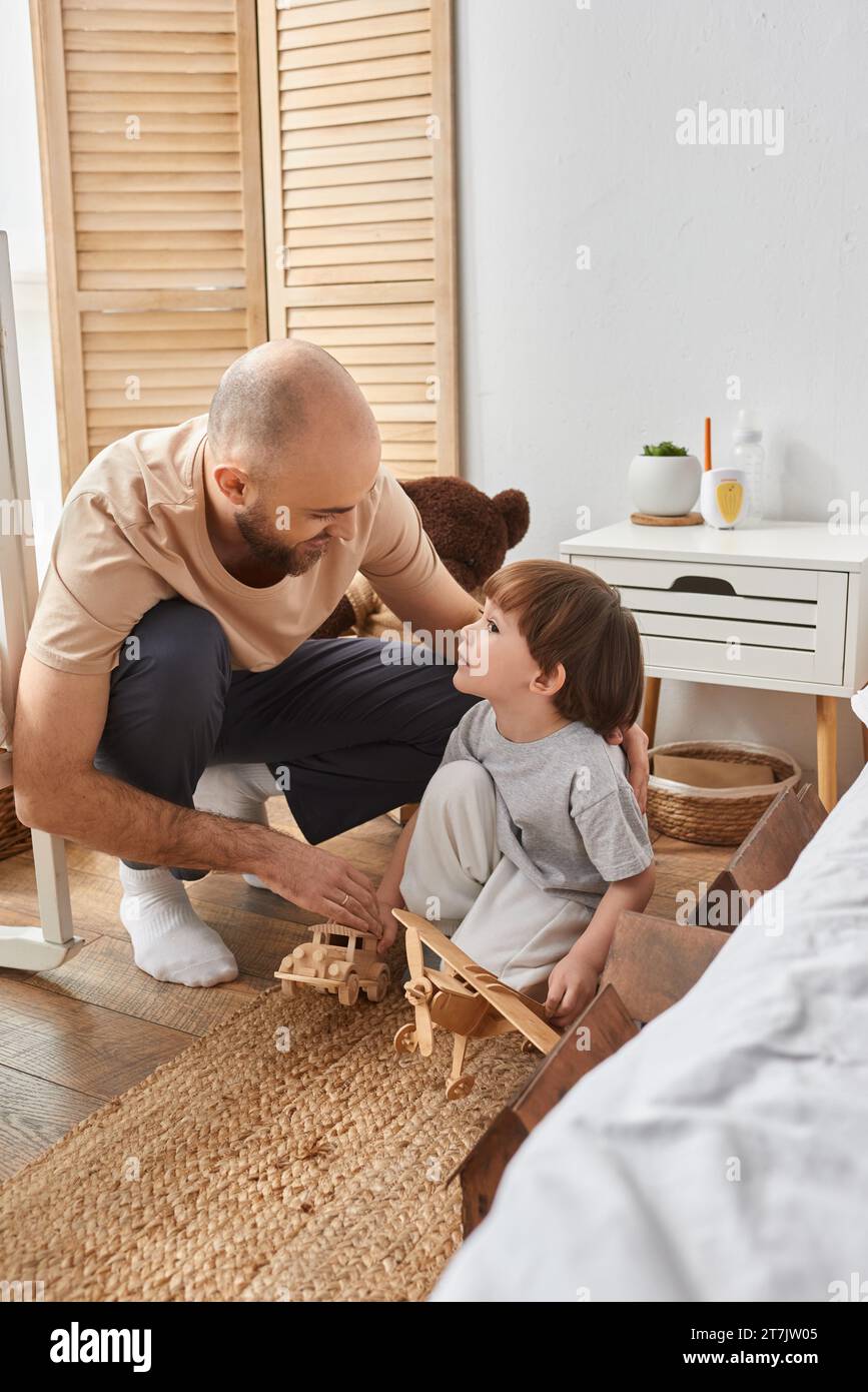 vertical shot of good looking bearded father playing with his little ...