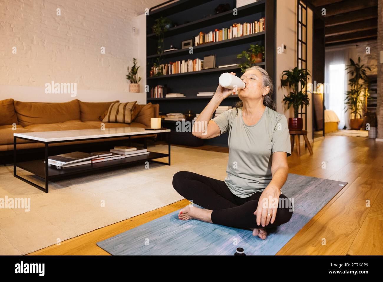 An active senior woman drinking water during a yoga workout session in ...