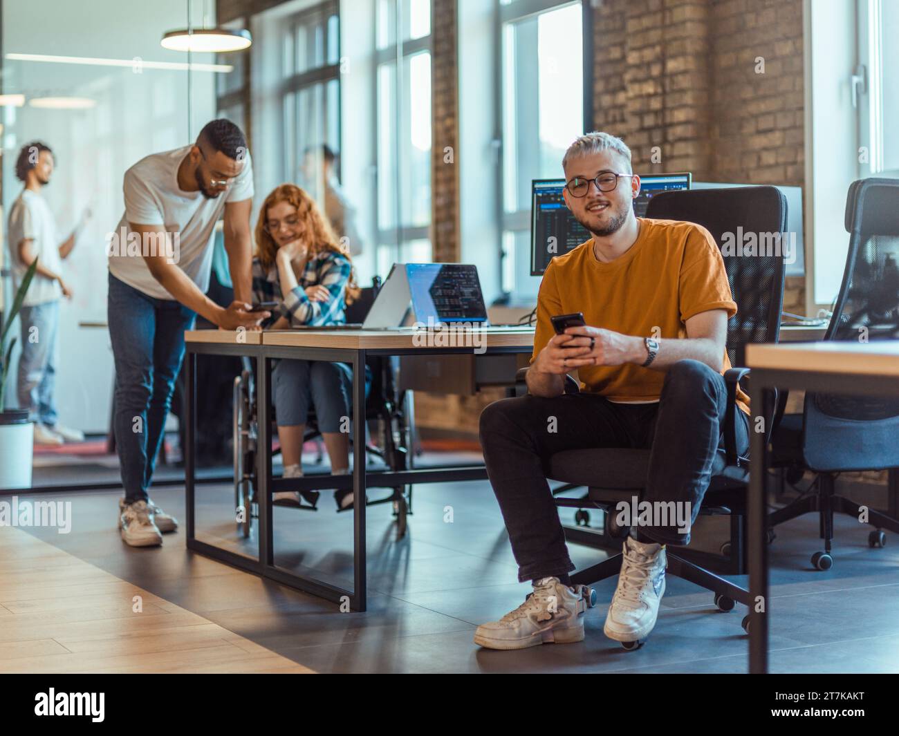 A diverse group of young business individuals congregates in a modern ...