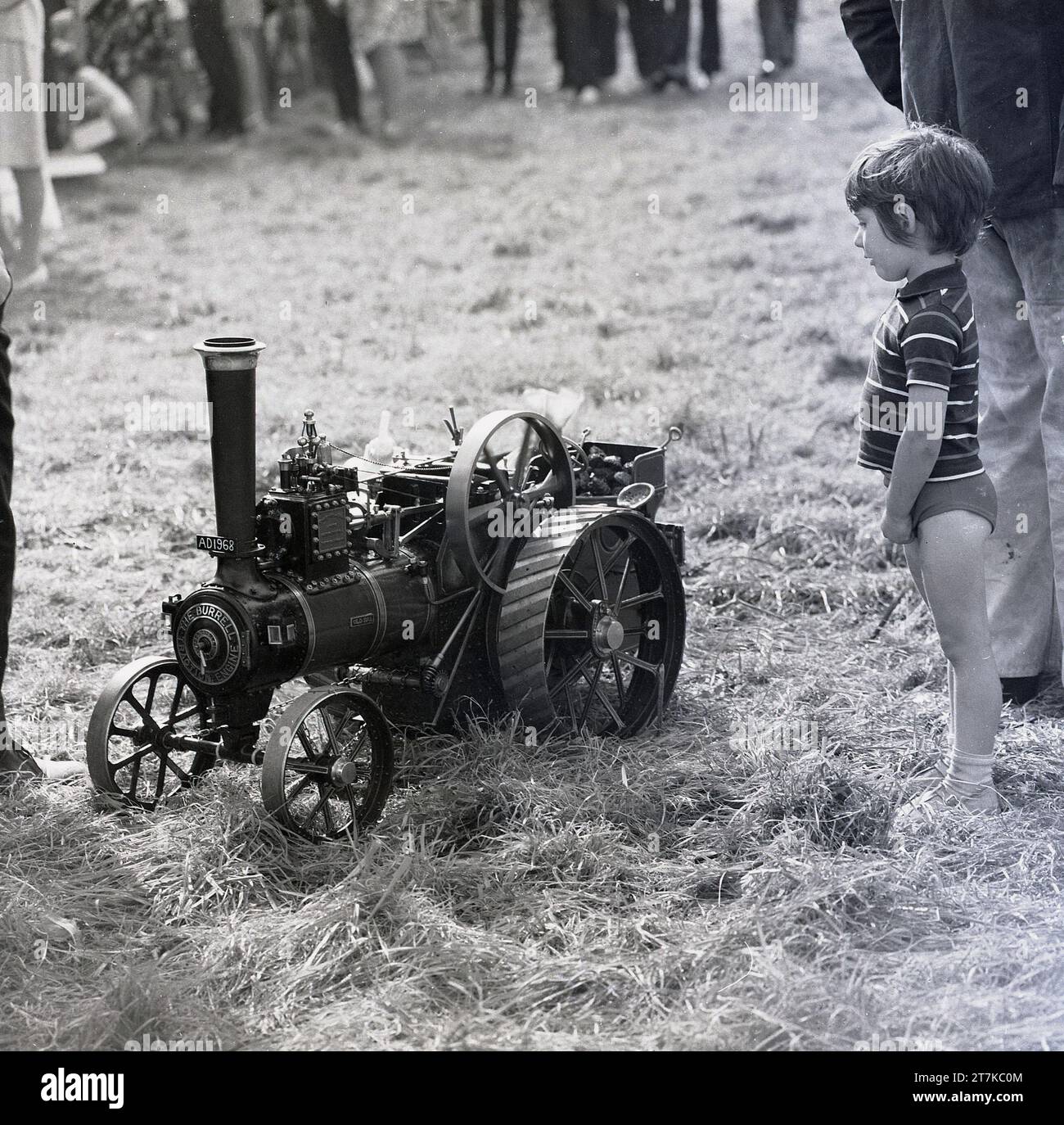 1970s, outside at a fairground, a little boy studies a miniature ...