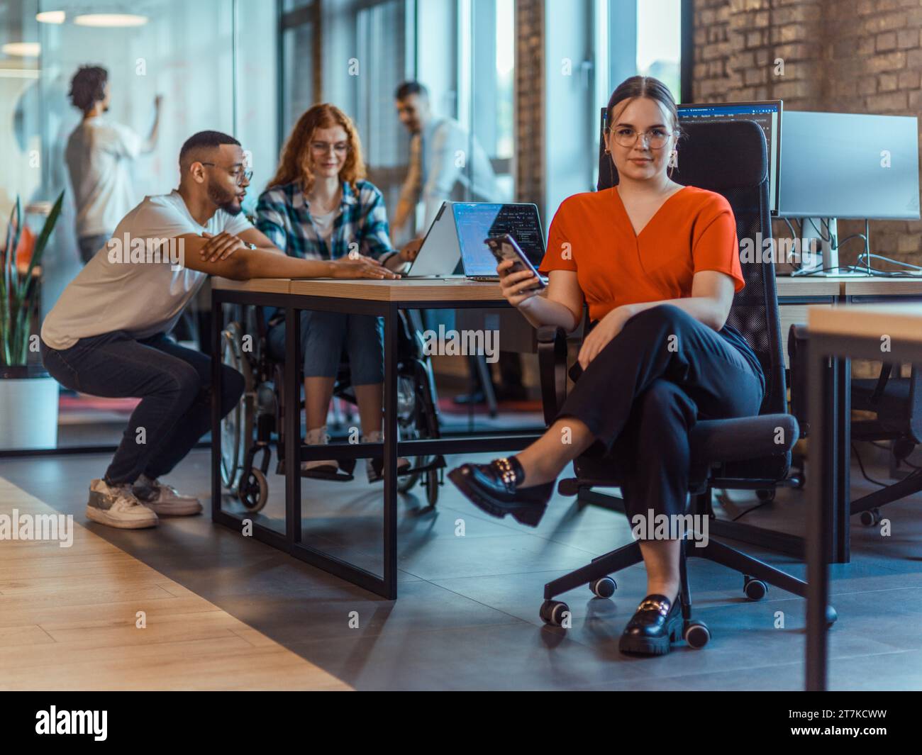 A diverse group of young business individuals congregates in a modern ...