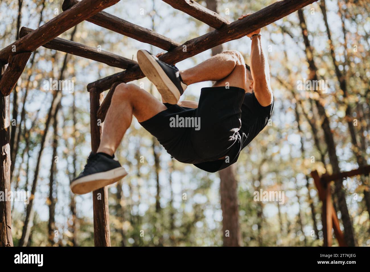 A man does pull ups outdoors in a forest. He enjoys a sunny day hiking ...