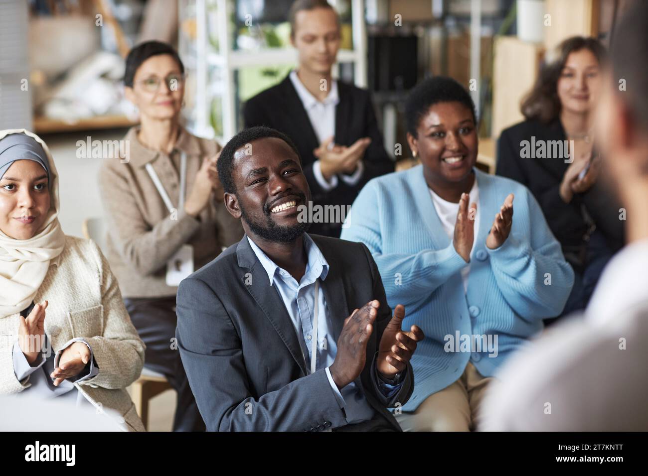 Group of young intercultural people sitting in row in front of speaker ...