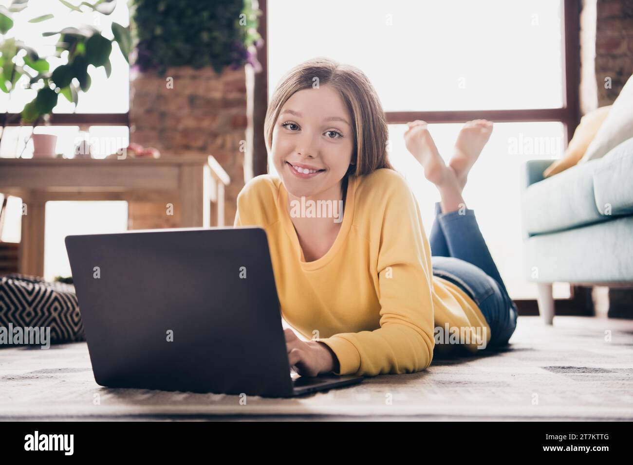 Portrait of lying floor barefoot teenager girl using artificial ...
