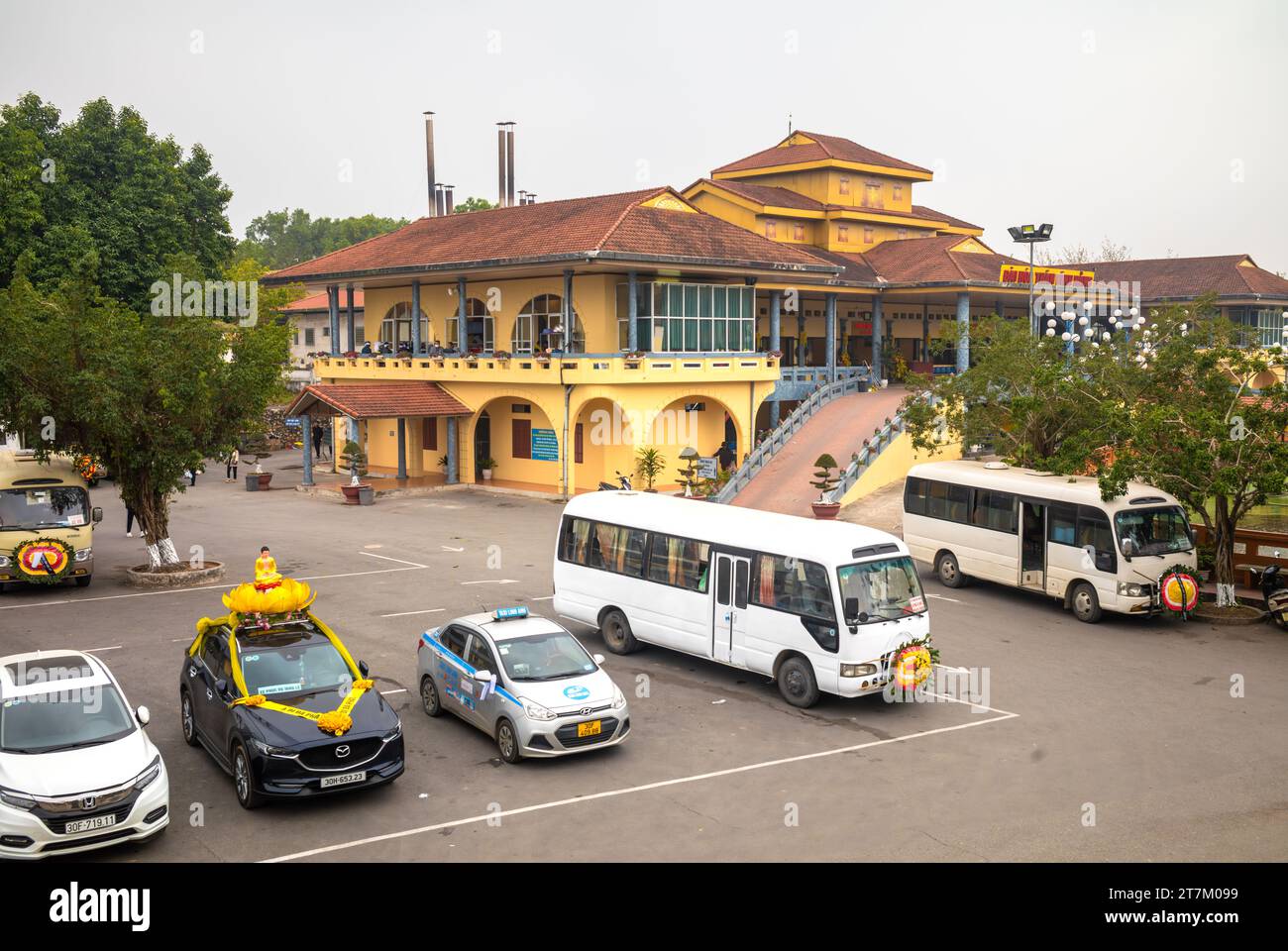 Funeral cars and buses with wreaths and a buddha parked outside Vinh ...