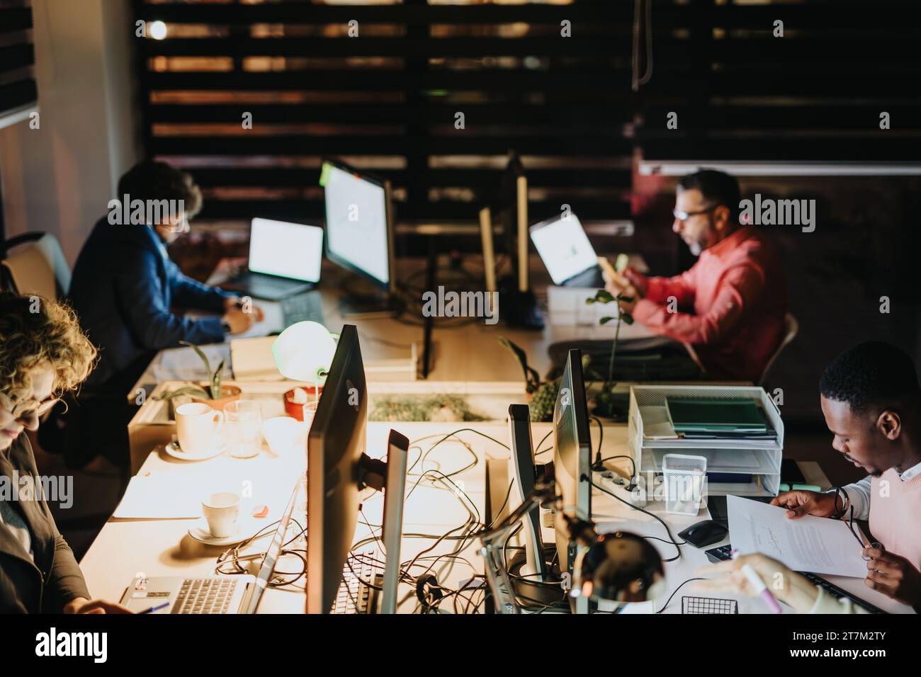 A diverse team collaborating on a project late at night, analyzing data ...