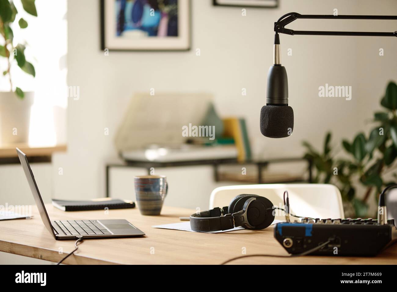 Microphone hanging over desk with headphones, soundboard and laptop ...