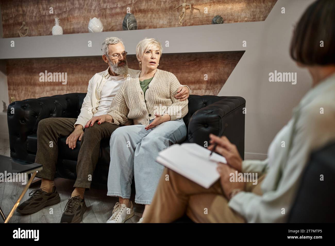 bearded man hugging worried middle aged wife looking at psychologist ...