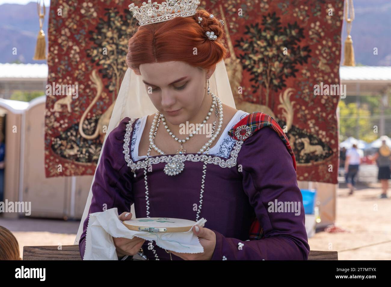 A reenactor dressed as Mary, Queen of Scots does embroidery at the ...