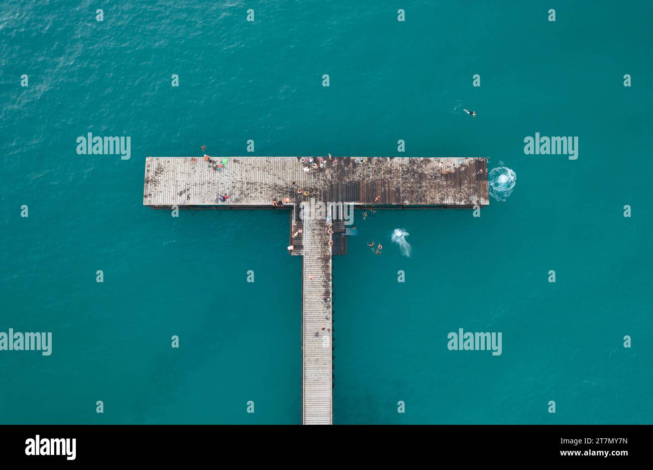 Drone aerial view of people diving in the sea from a jetty. Healthy ...