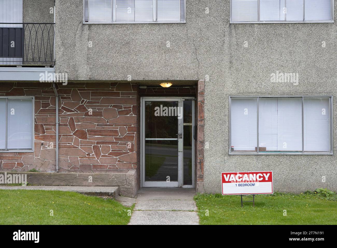 Vacancy sign on lawn in front of older apartment building entrance ...