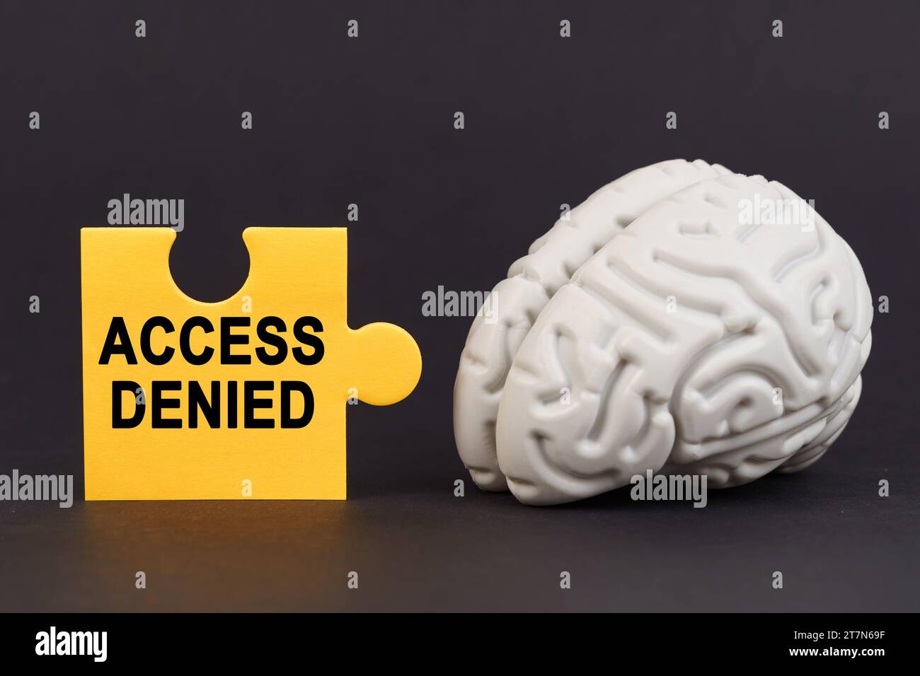 On a black surface there is a brain and a yellow puzzle with the ...