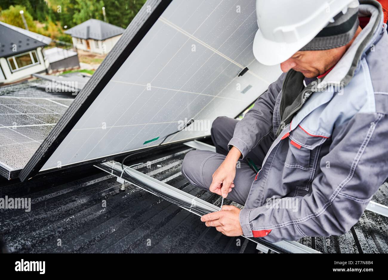 Male worker securing cables by special tie. Solar battery installation ...
