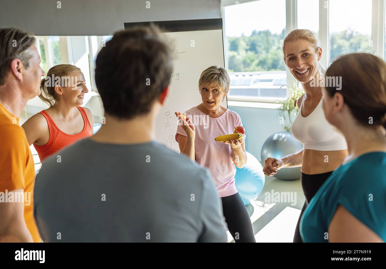 Group of people discussing with a female trainer about nutritional ...