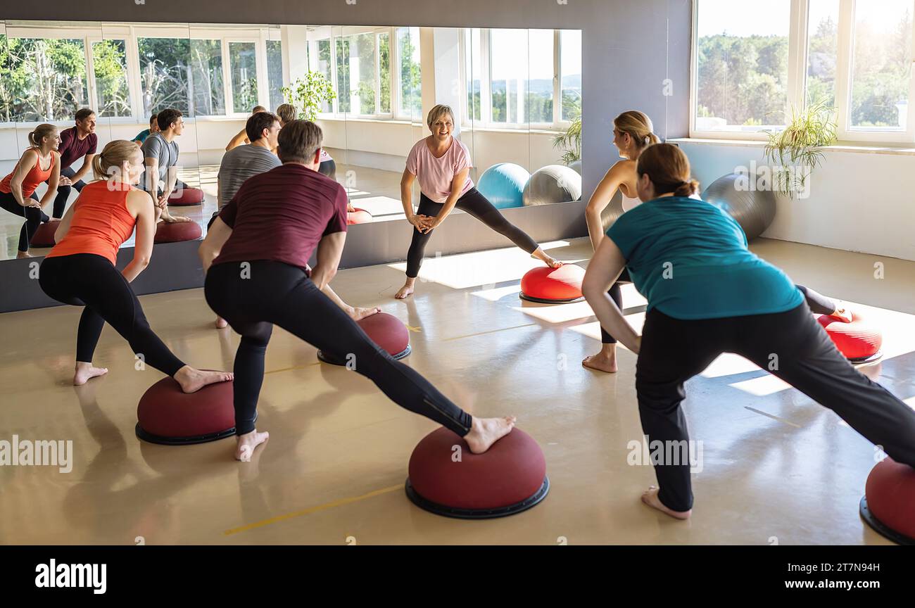 Group of people stretching on Bosu Balls in a fitness class with large ...
