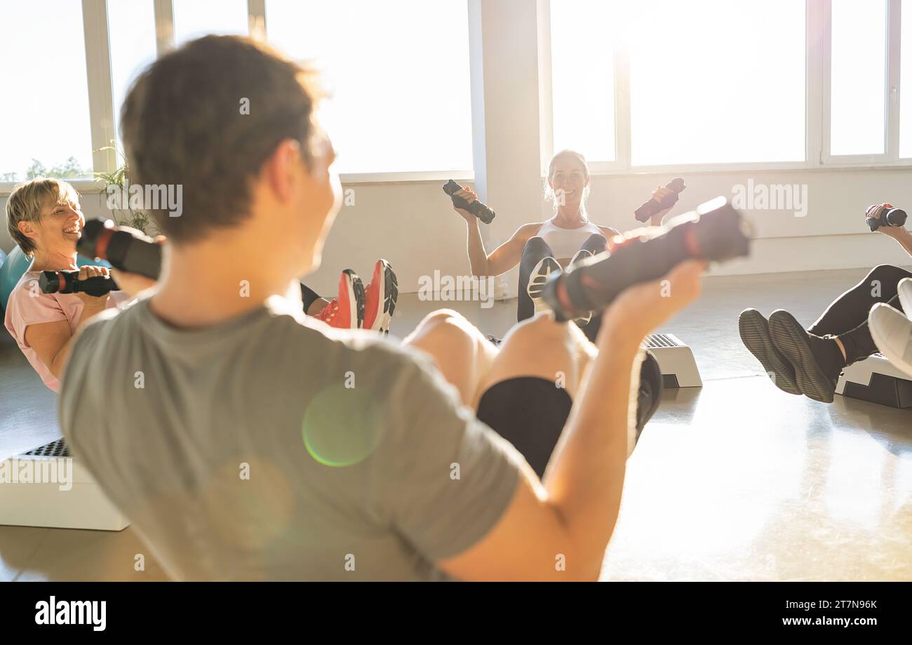 Gym class doing seated dumbbell exercises, sunlit room, joyful ...