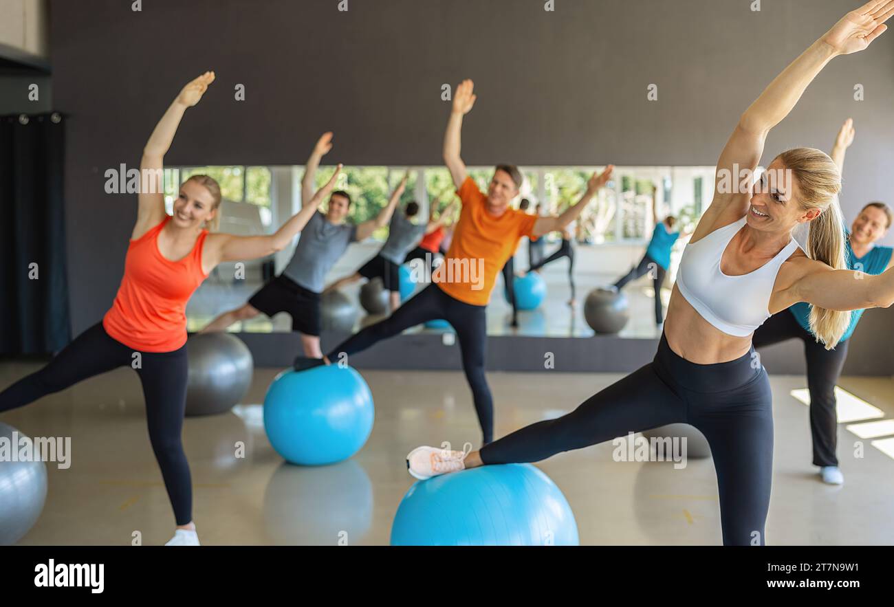 Group of happy people in a receding line doing pilates in a gym ...