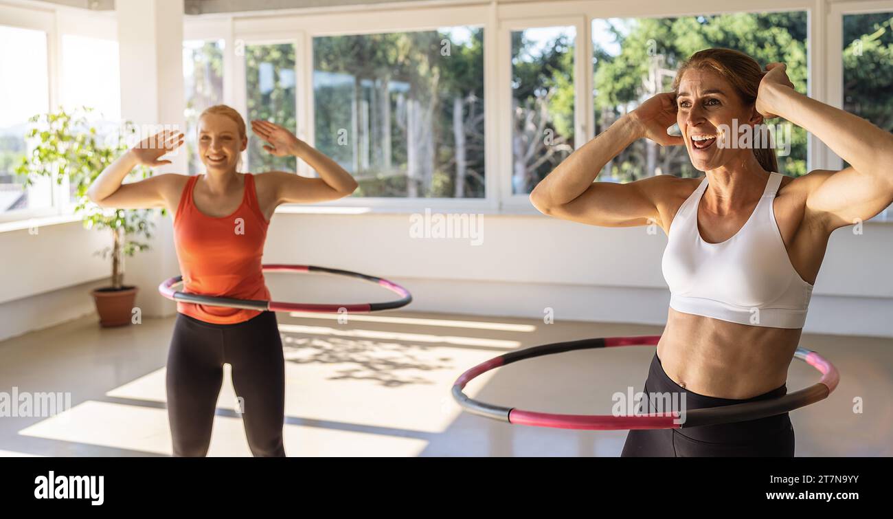 Woman doing hula hoop during an exercise class in a gym. Healthy sports ...