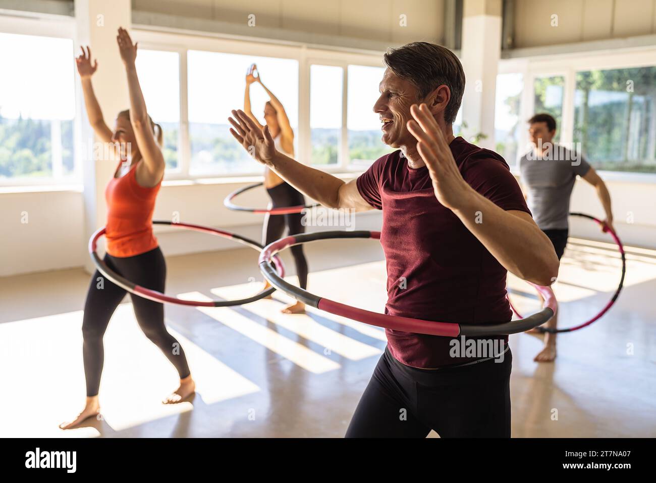 Team Sport women and men doing hula hoop in step waist hooping forward ...