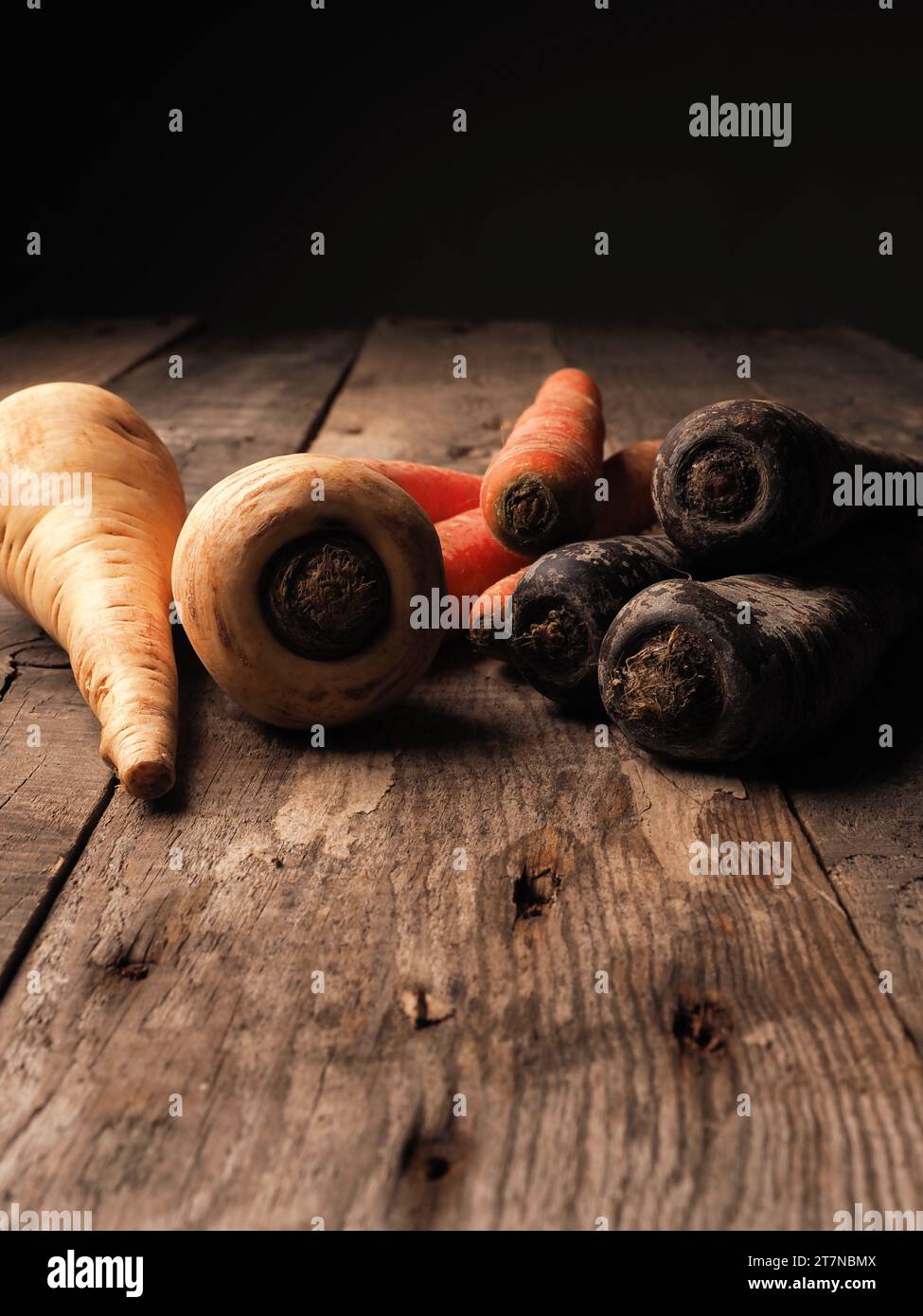 Three different root vegetables on a rustic wooden kitchen table on a ...