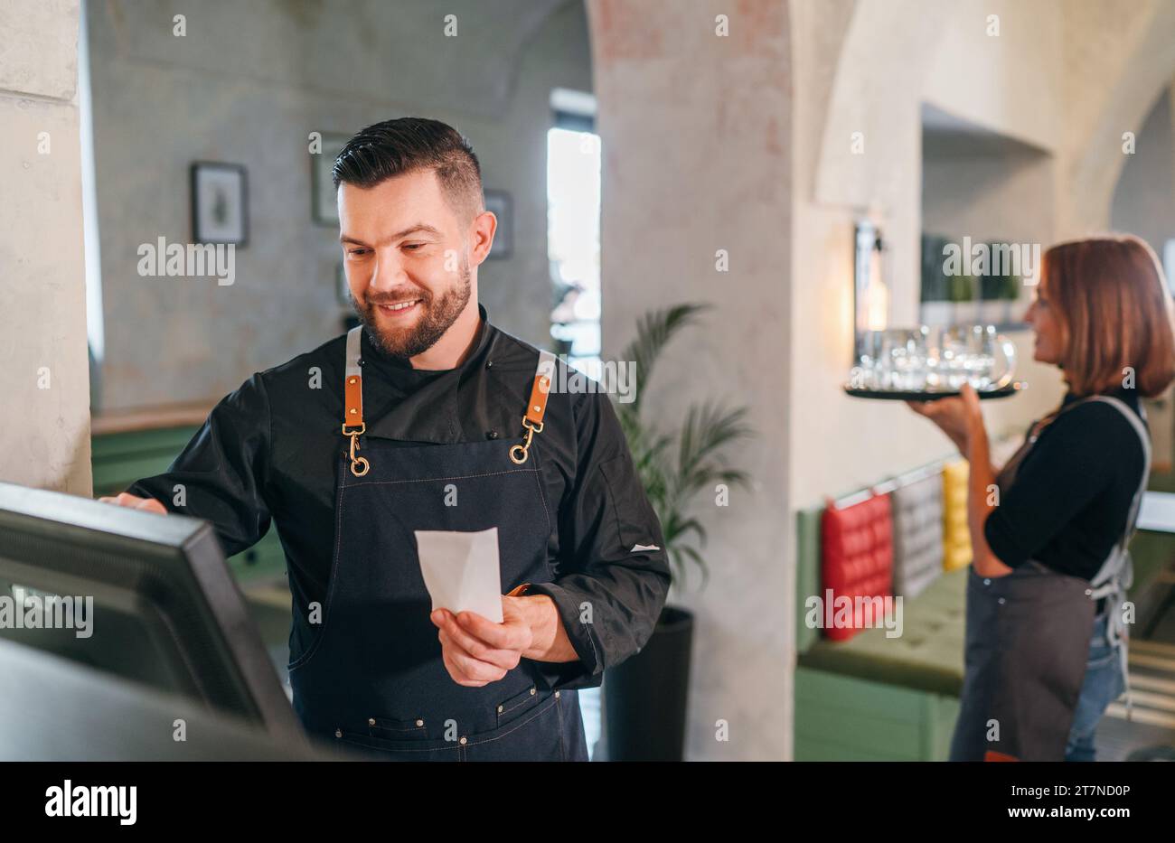 Stylish bearded smiling waiter dressed black uniform using point of ...