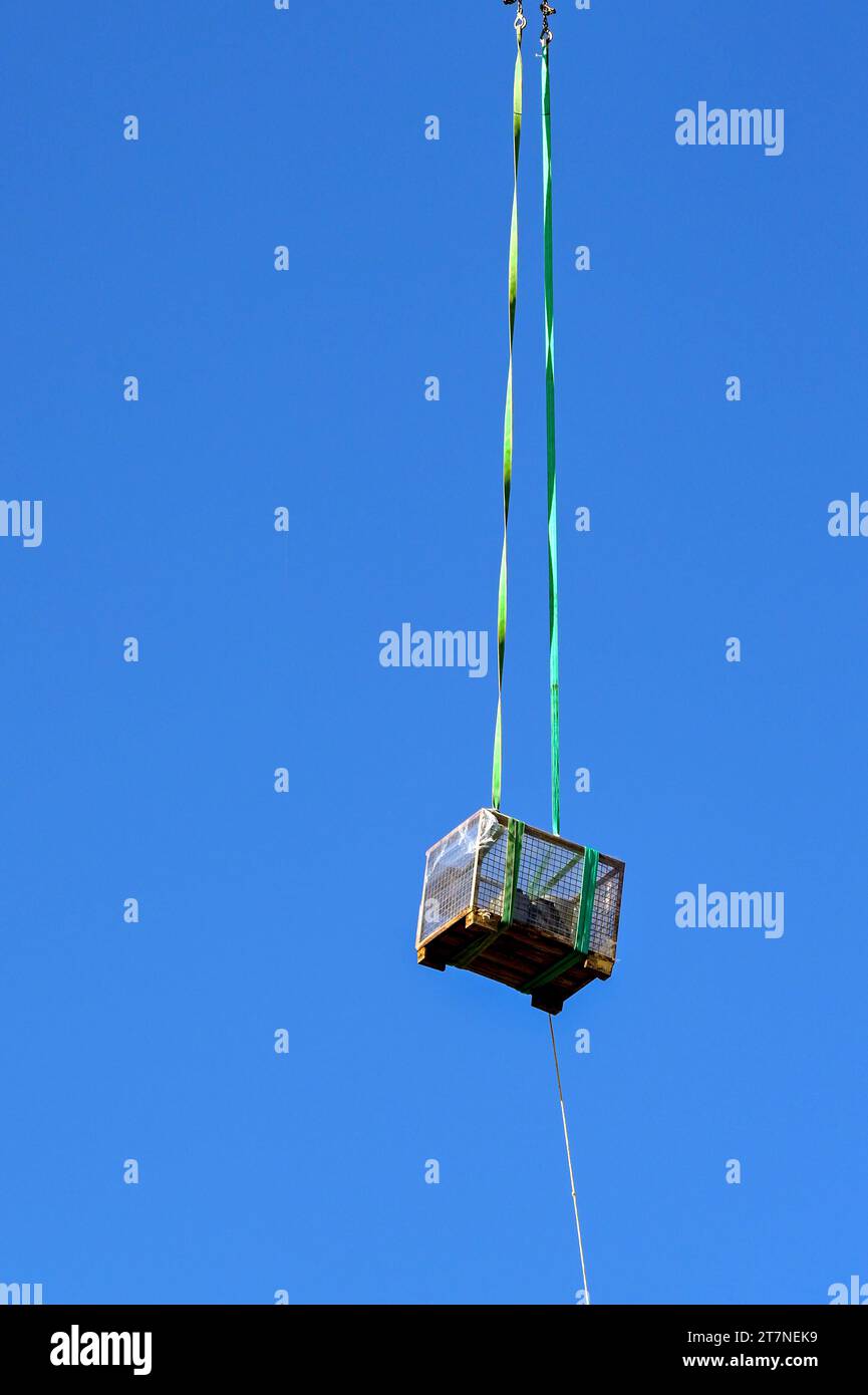 Large metal container of building materials being lifted over a ...