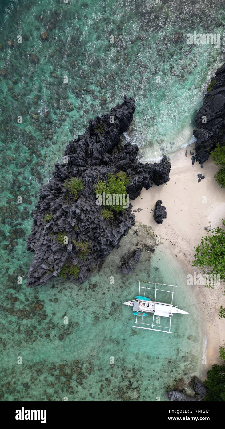 Aerial shot of a boat resting on a sandy beach adjacent to a tranquil ...