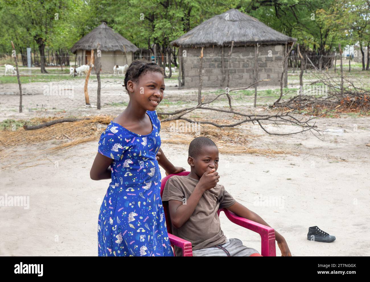 a boy and a girl african kids in the sandy back yard of their shack in ...
