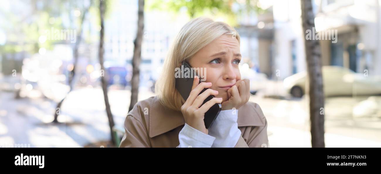 Image of young stressed, upset woman, talking on mobile phone with ...