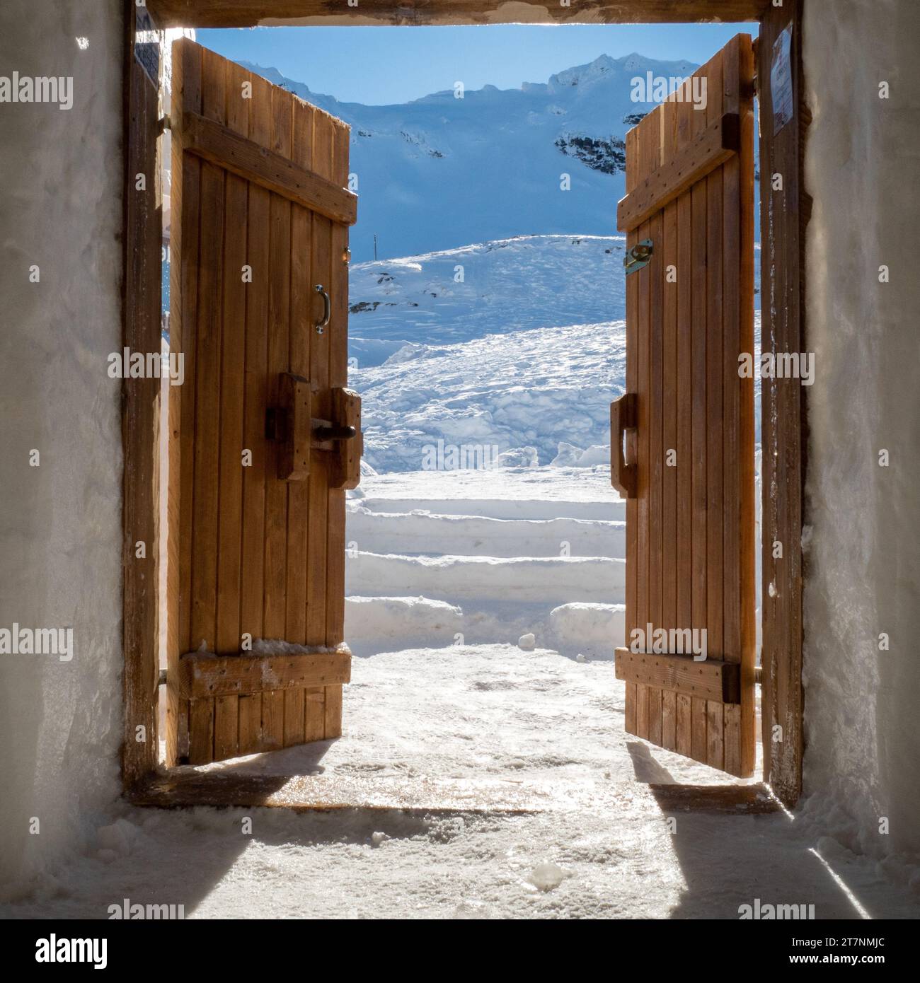 A pair of wooden doors open to a stunning view of a mountain range ...