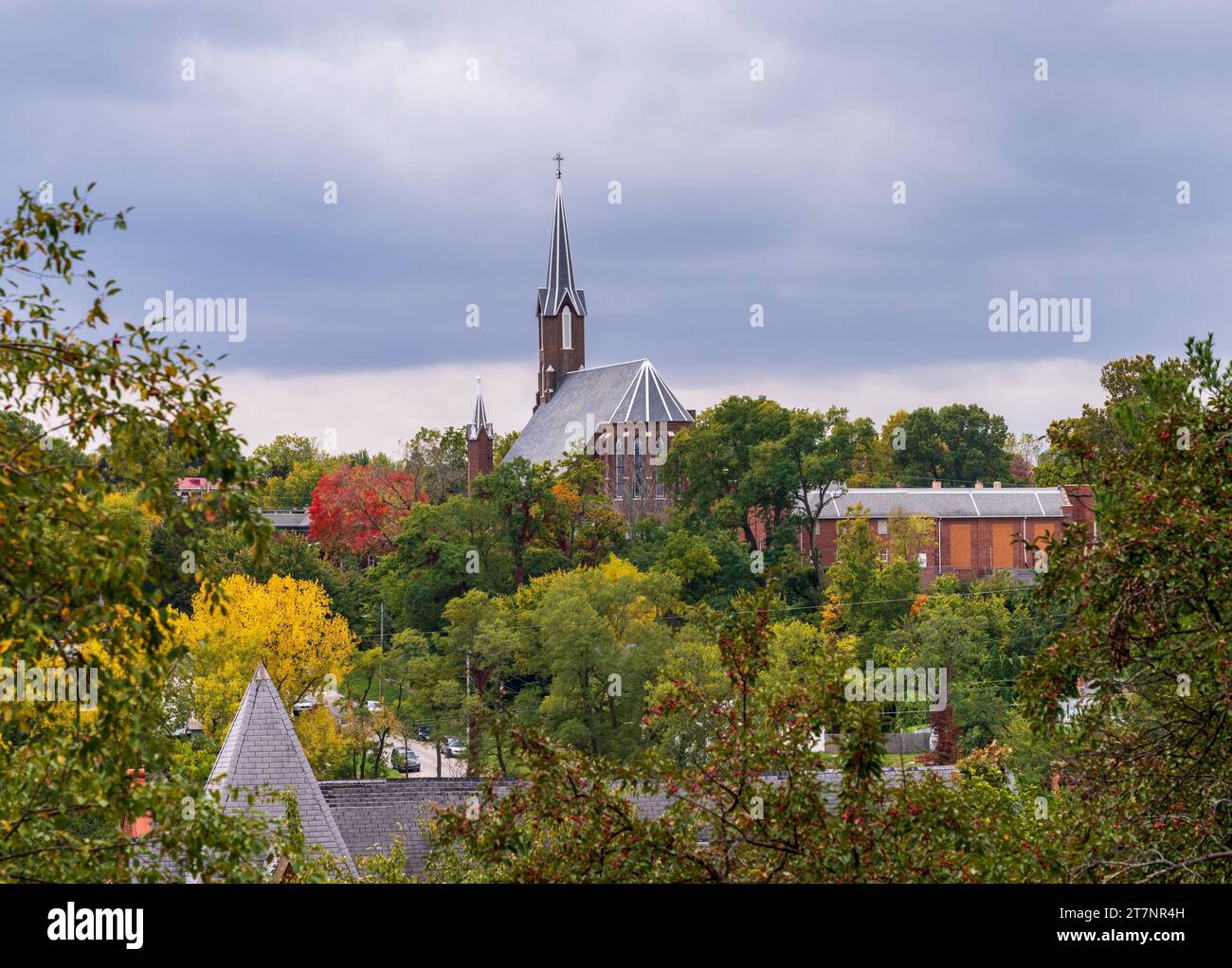 Unusual spire of St John Catholic church among fall trees in the city ...