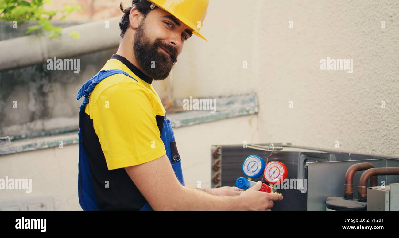 Efficient technician looking at refrigerant levels in external air ...