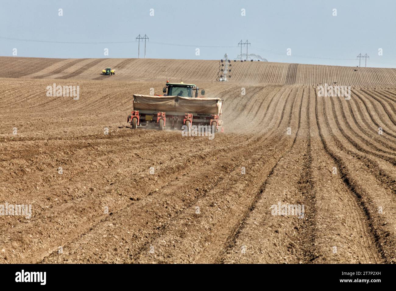 Two tractors with planting implements, work in the fertile farm fields ...
