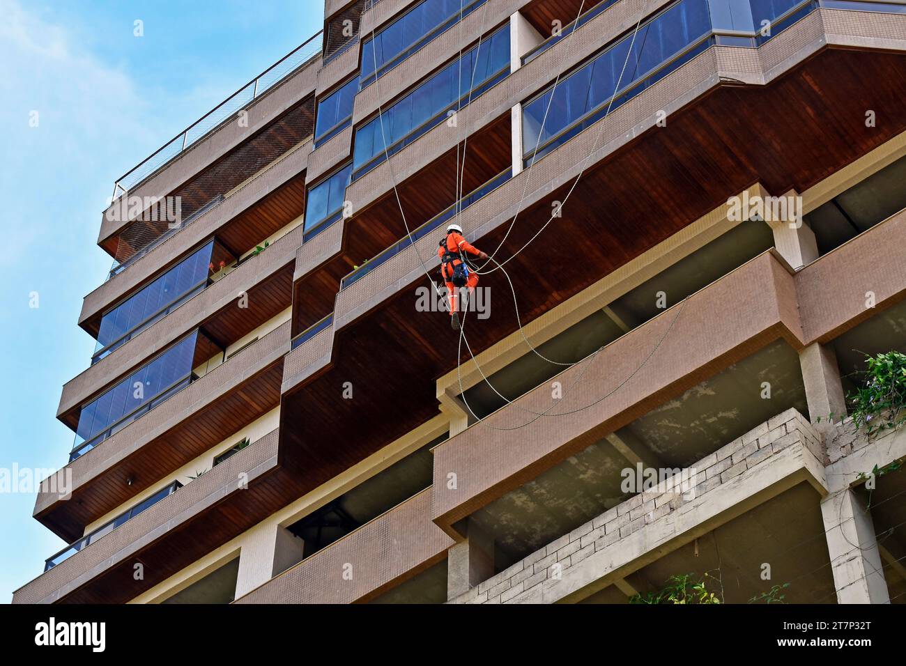 Man hanging from steel cables to clean the facade of a residential ...