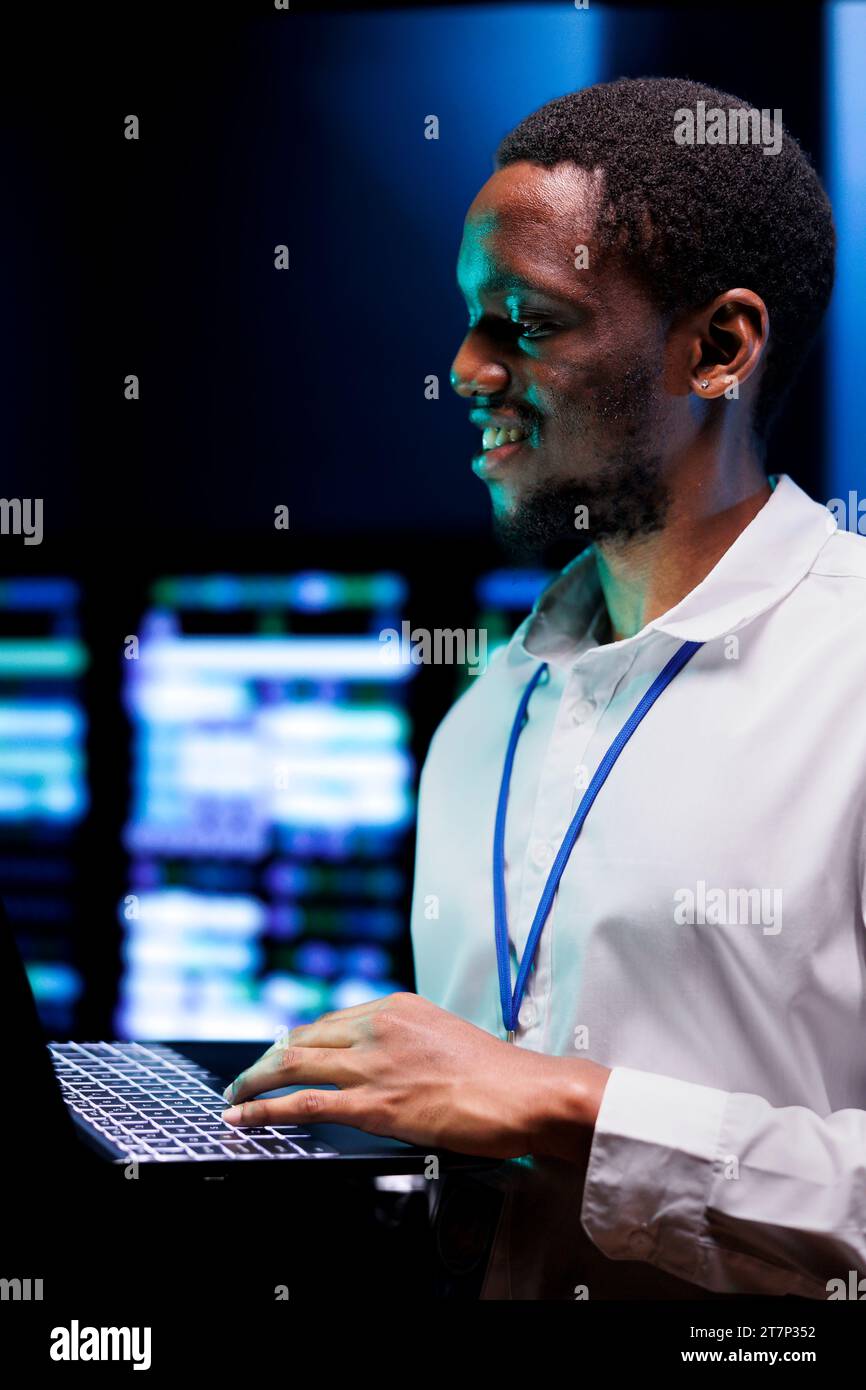 Happy supervisor monitoring server racks providing vast computing resources and storage. Data ...