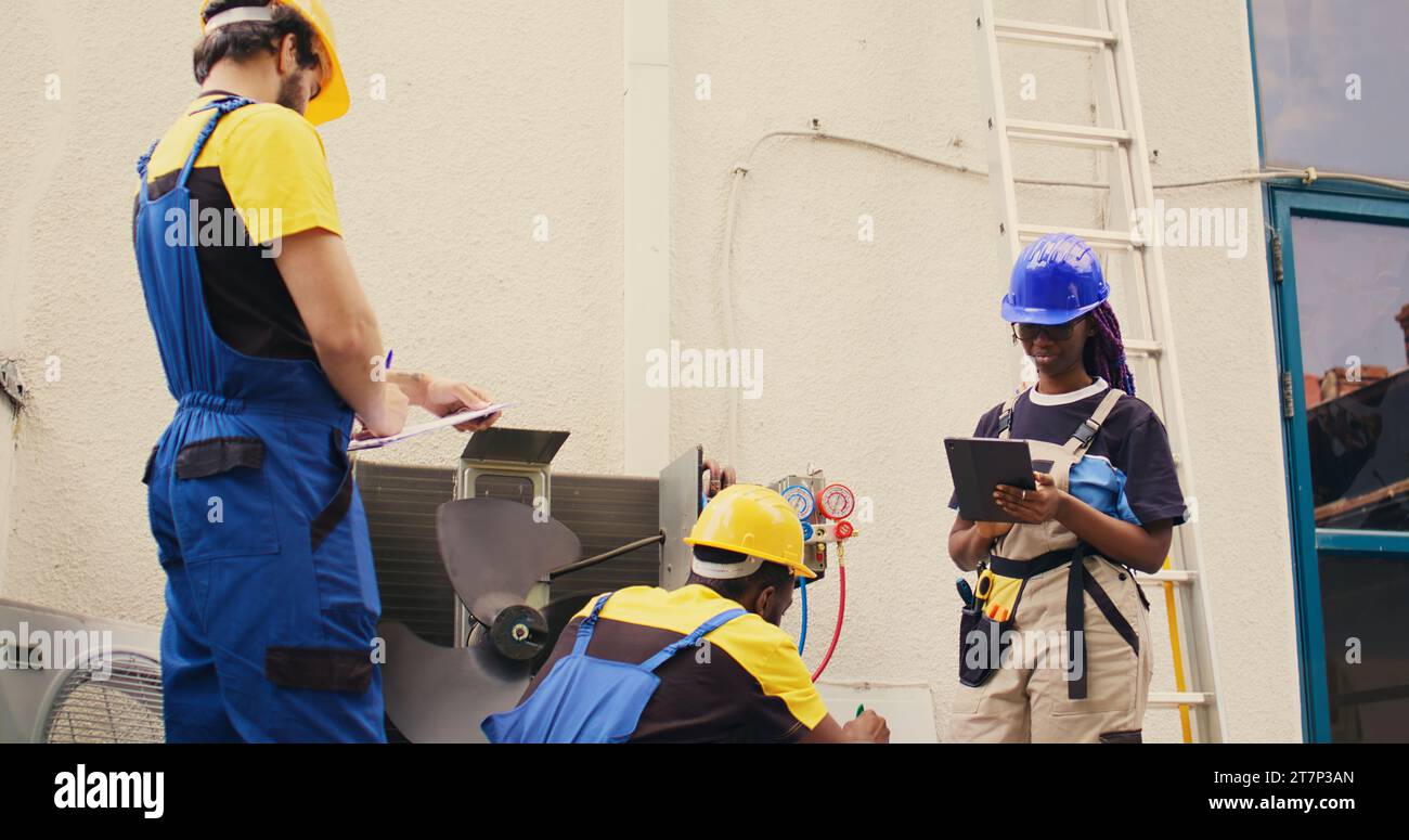 Trained diverse teamworking servicemen cleaning external condenser ...